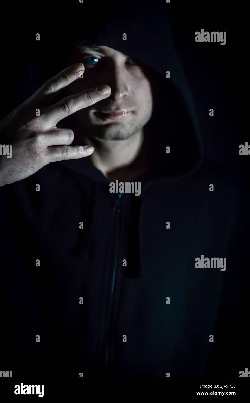 Portrait of a young hooded man with blue eyes making a bad gesture with ...