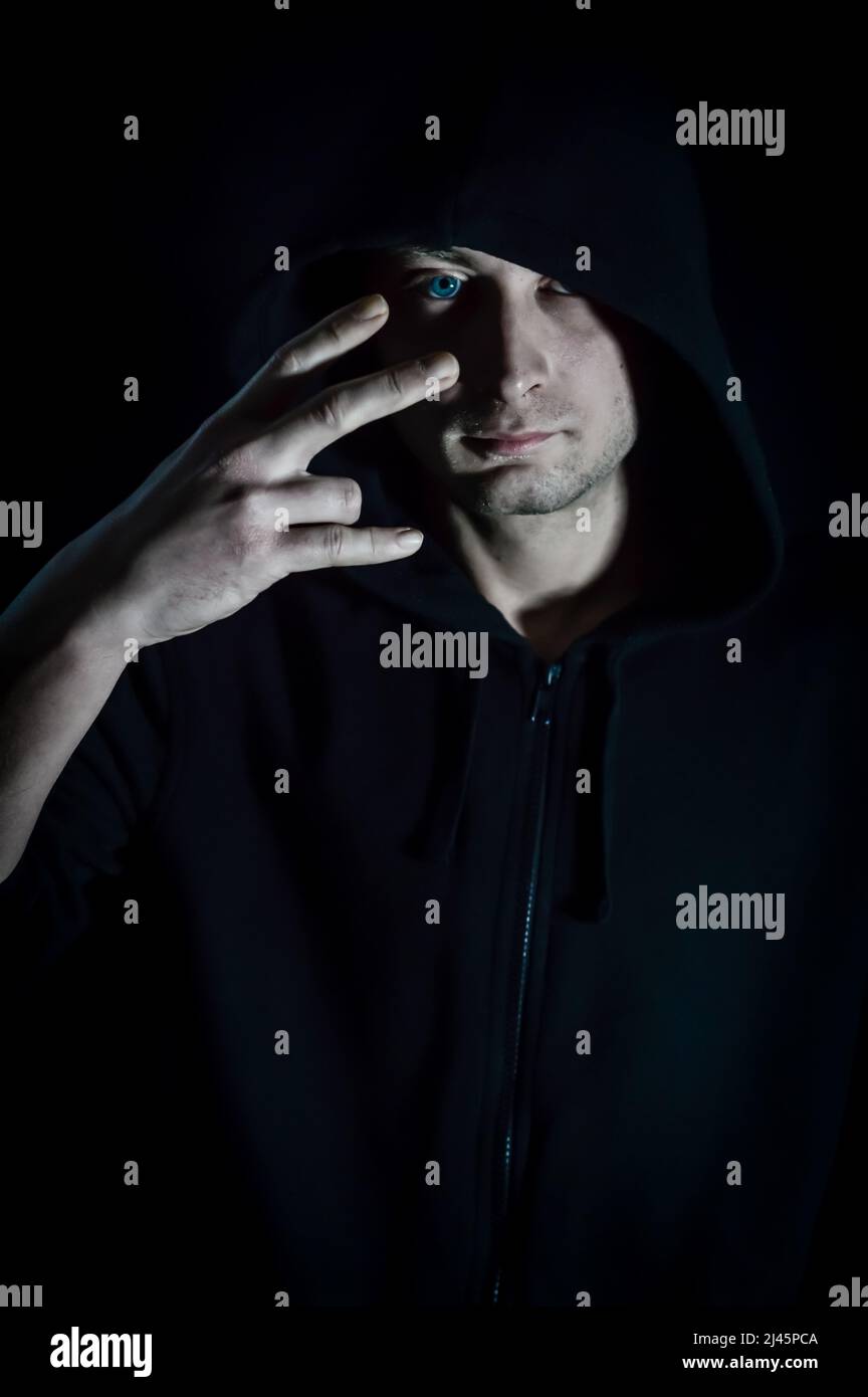 Portrait of a young hooded man with blue eyes making a bad gesture with ...