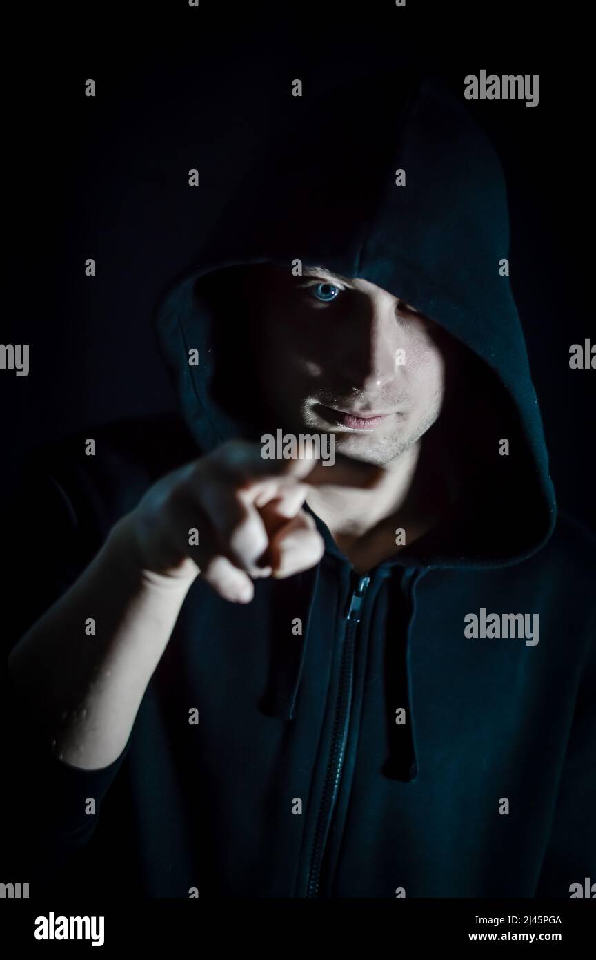 I am watching you - young hooded man making a two-finger gesture ...