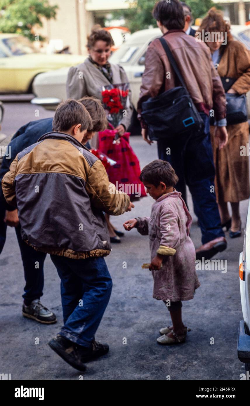 Two boys give coins to a gypsy child begging on the street, Moscow, May ...