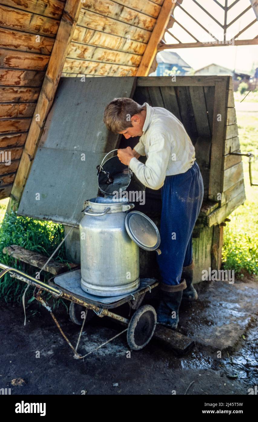 A boy filling a milk churn with water from a well on his family's farm ...