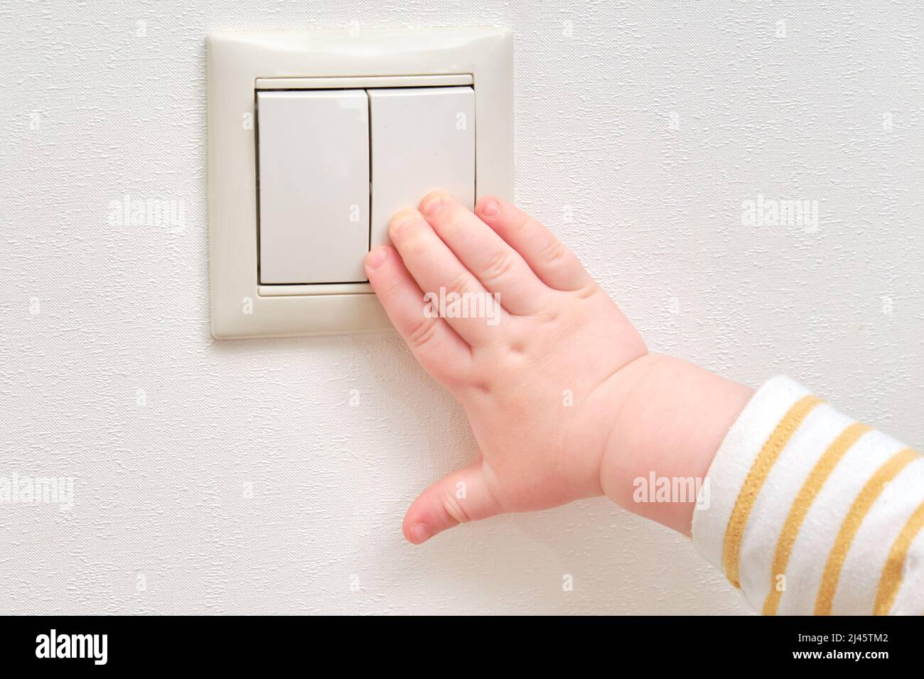 Toddler baby boy turns the light on and off with an electric switch ...