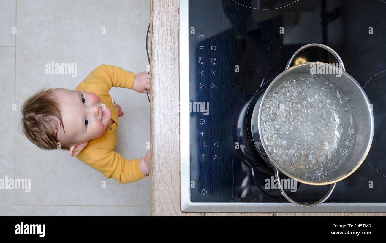 Toddler baby boy looks at a pot of boiling water. Child safety issues ...
