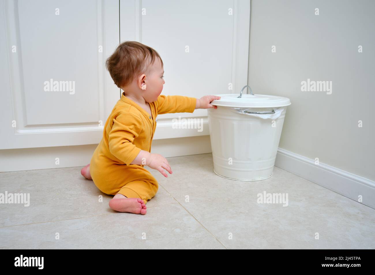 Toddler baby boy opens a trash can with household waste. Children's ...