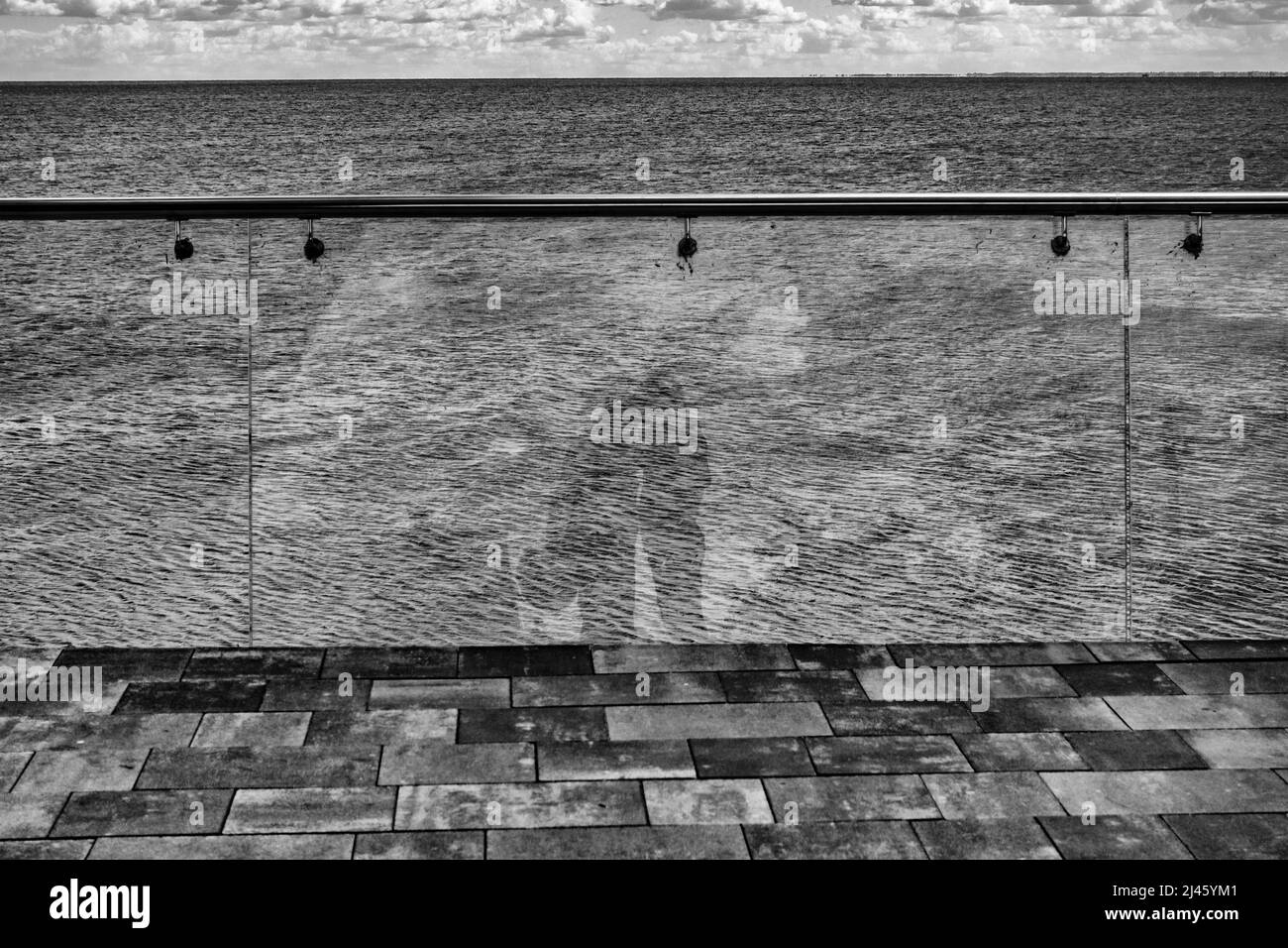 Reflection in a glass of a pair of people on the background of the sea ...