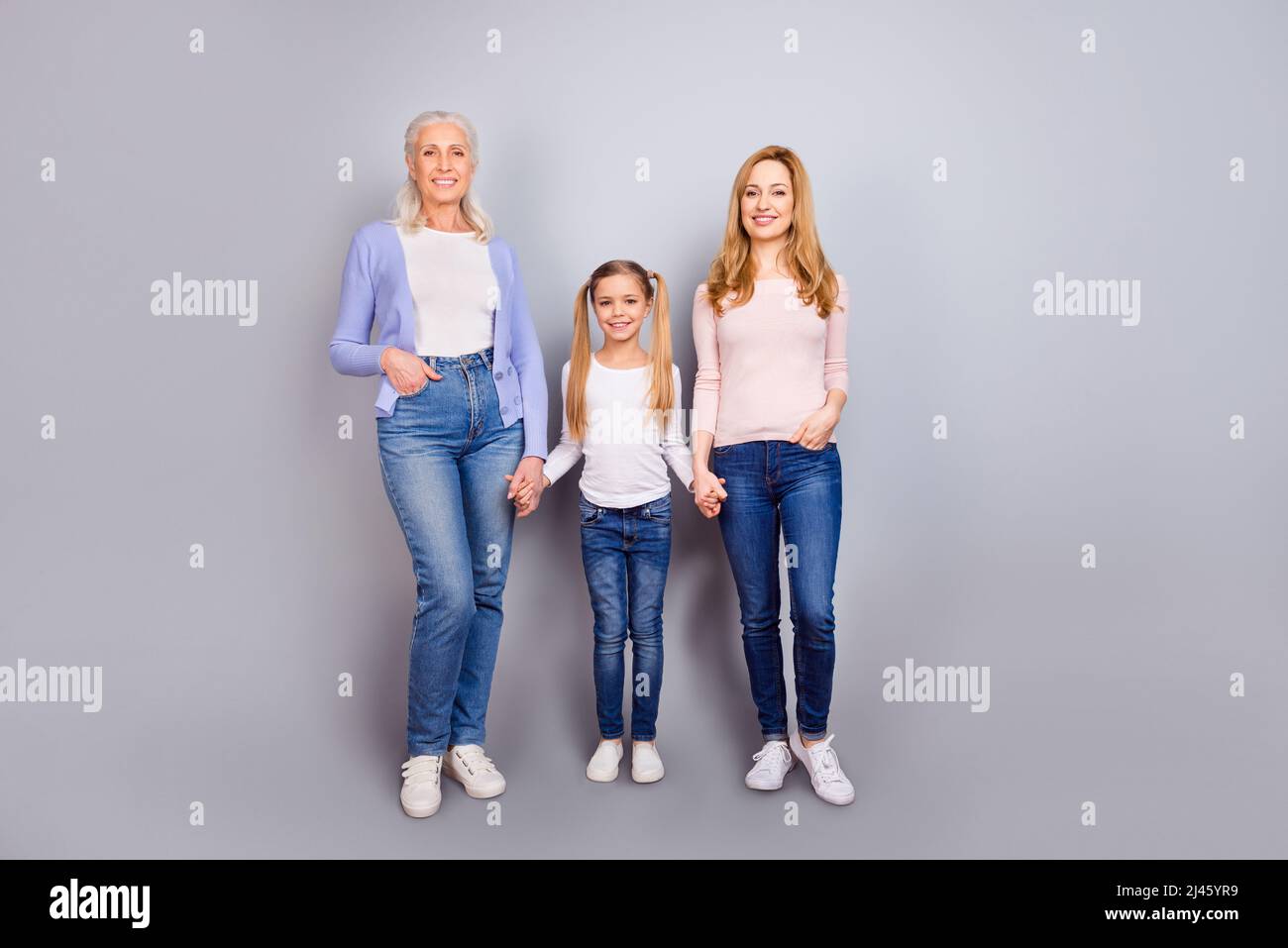 Full size photo of three cheerful friendly people standing hold arms ...