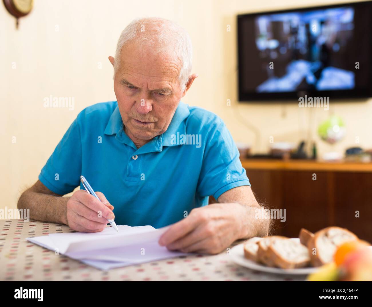 Concentrated elderly man filling up papers at home table Stock Photo ...