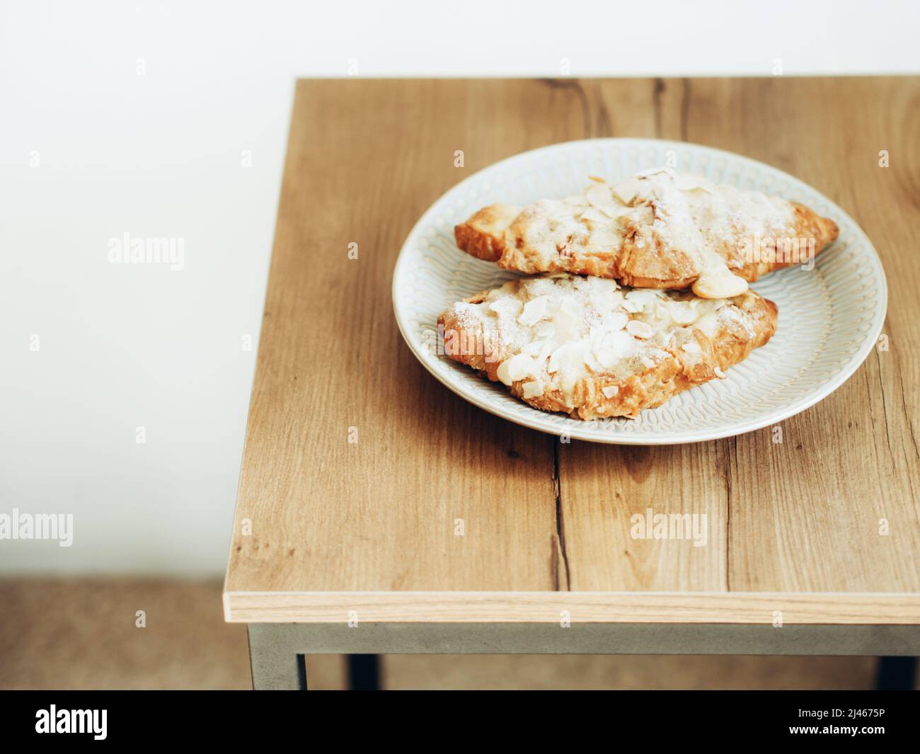 Traditional French breakfast croissant with almonds on plate on wood ...
