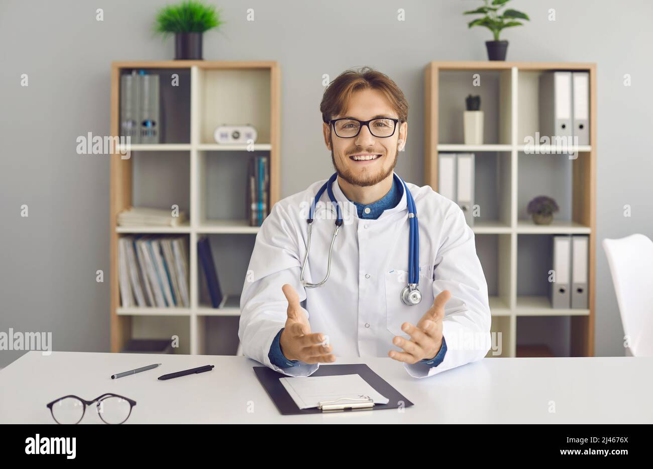 Webcam portrait of doctor sitting at desk and giving consultation via ...