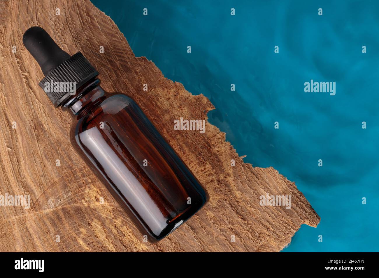 Cosmetic bottle with incendiary, top shot. Brown bottle on wood, blue ...
