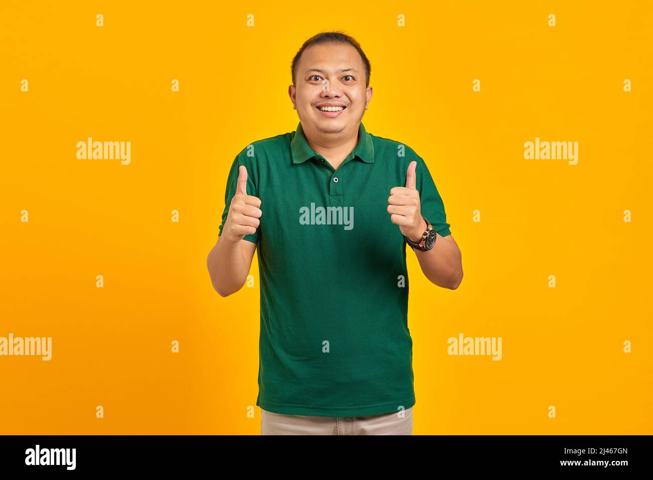 Cheerful handsome asian young man showing thumbs up gesture isolated on yellow background Stock ...