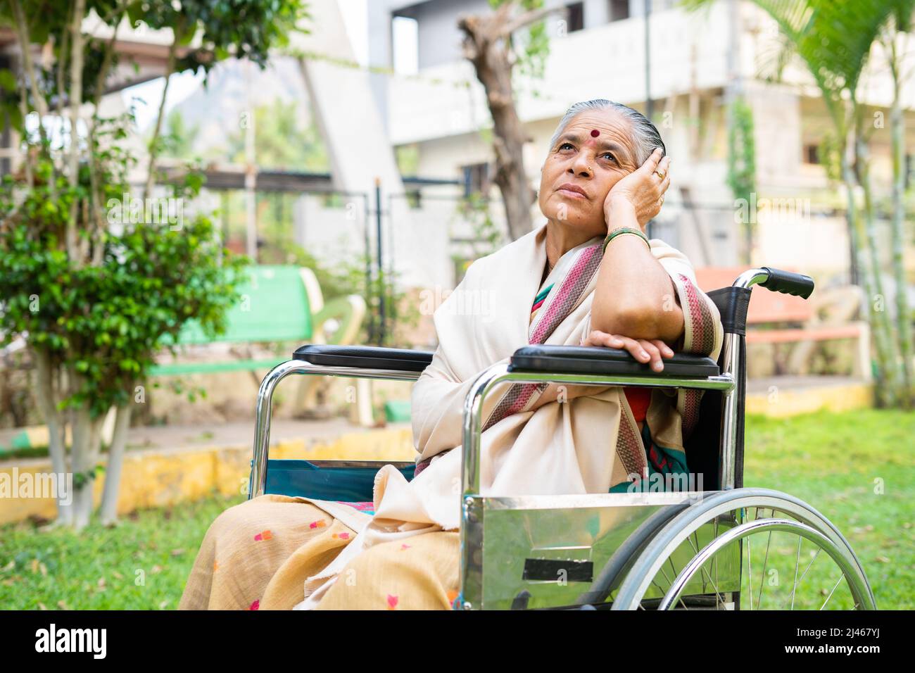 Deep thinking senior woman with disability on wheelchair at park ...