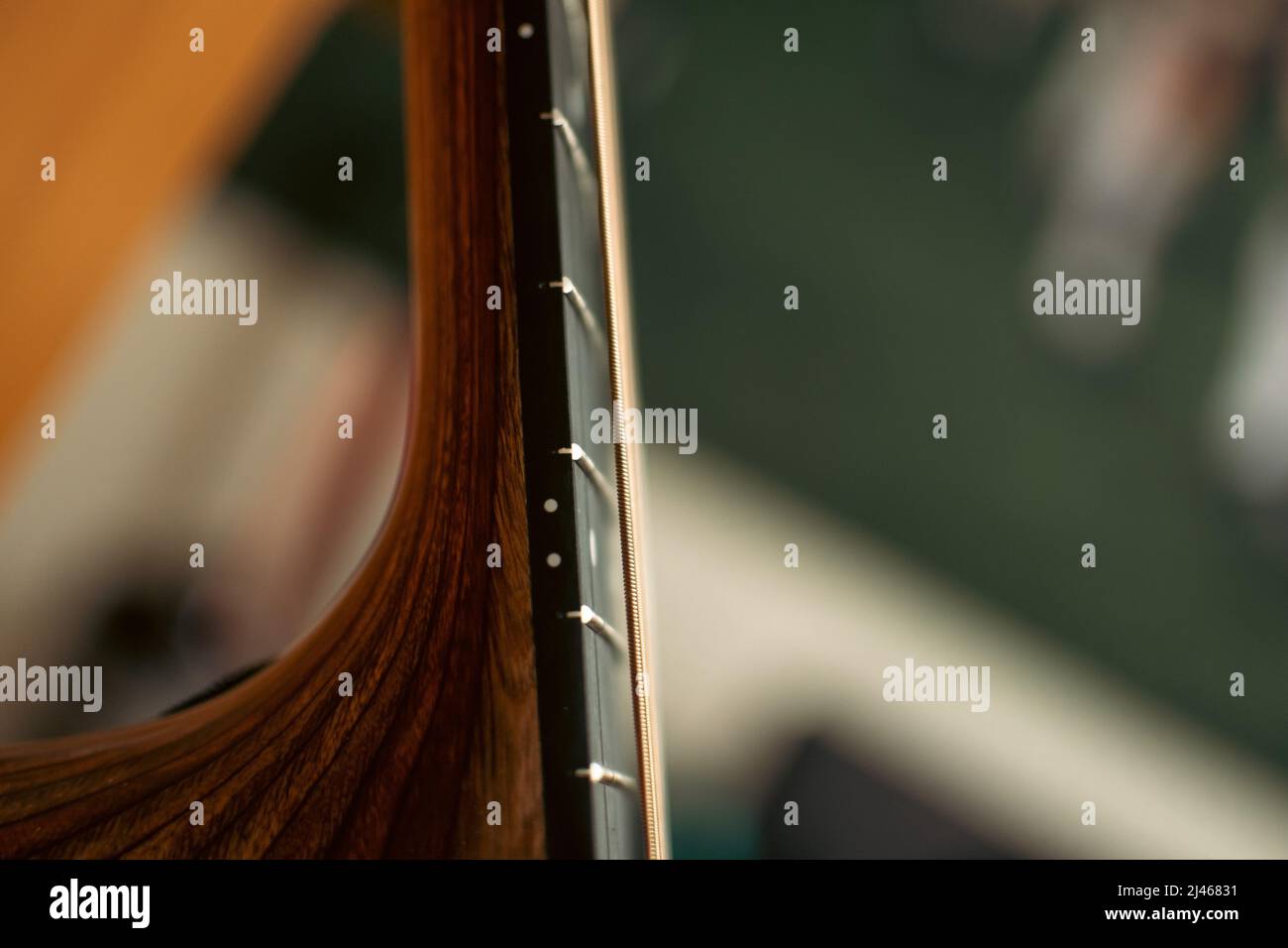 A close up shot of the neck of a wooden acoustic guitar with bronze ...