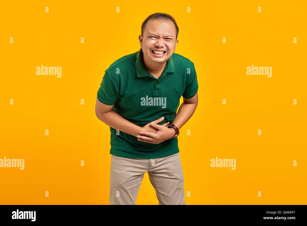 Attractive asian young man laughing out loud at funny on yellow ...