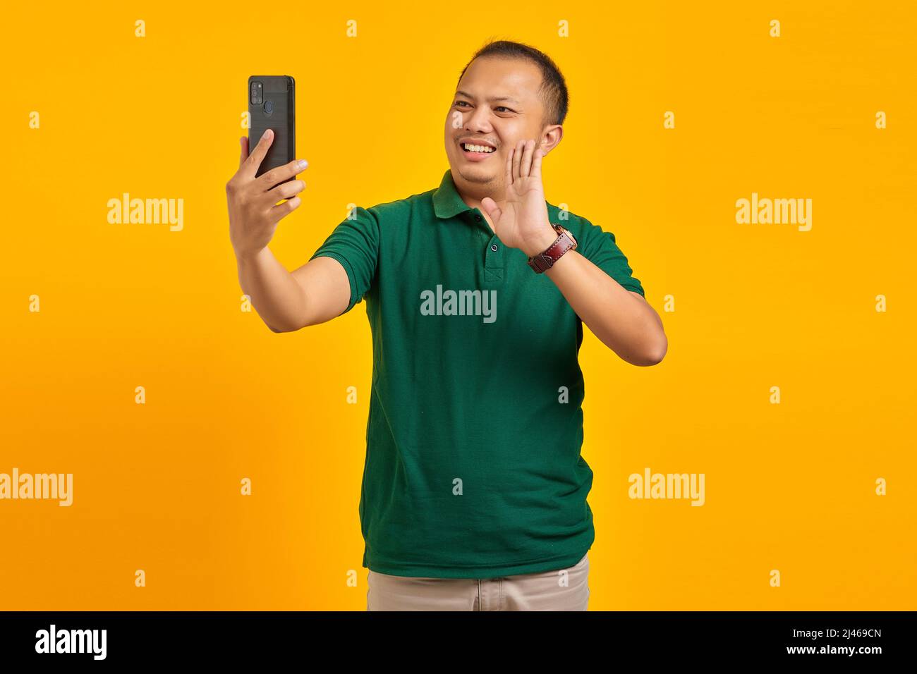 Happy young man having video call and waving a hand at smartphone ...