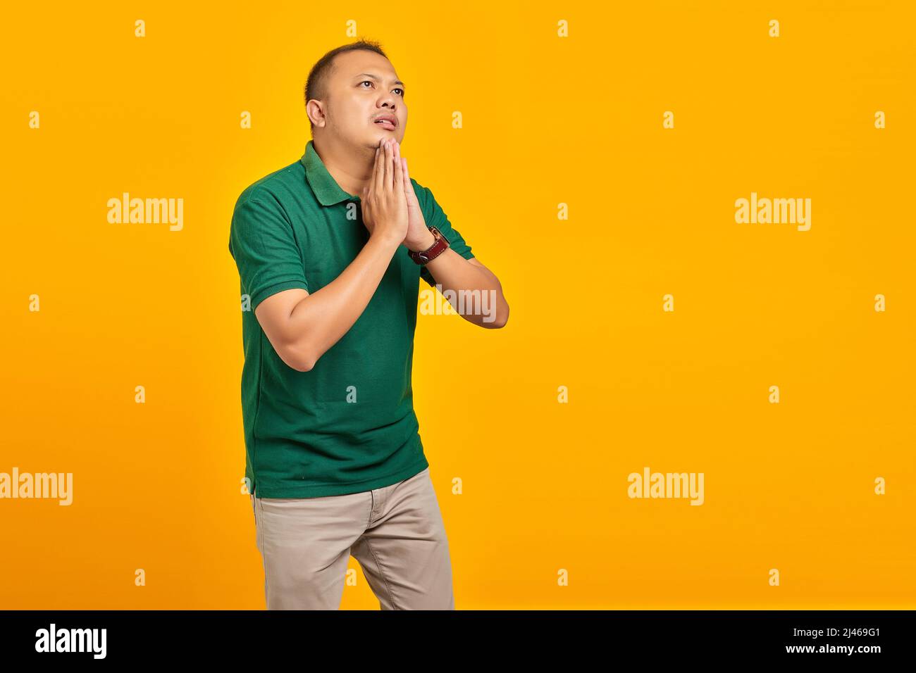 Portrait of Asian young man pleading and praying with hands together ...