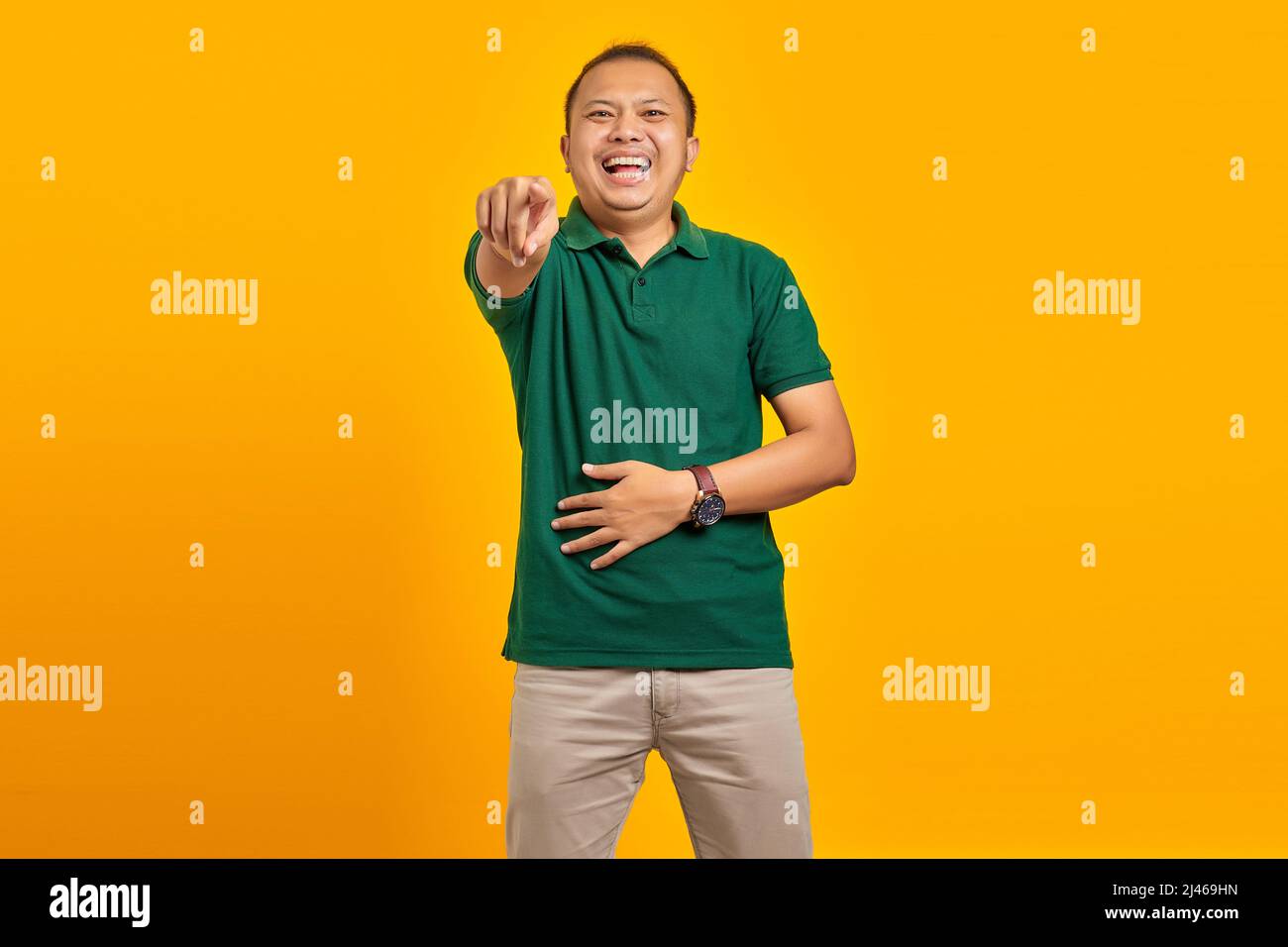 Portrait of young Asian man showing loud laughter with hand on stomach ...