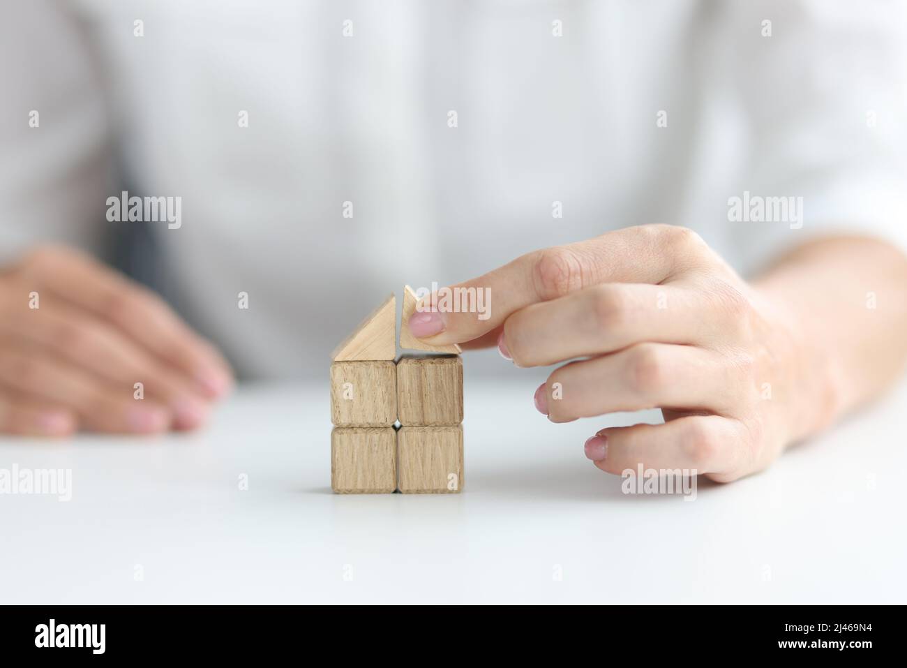 Person builds house from wooden cubes closeup Stock Photo - Alamy