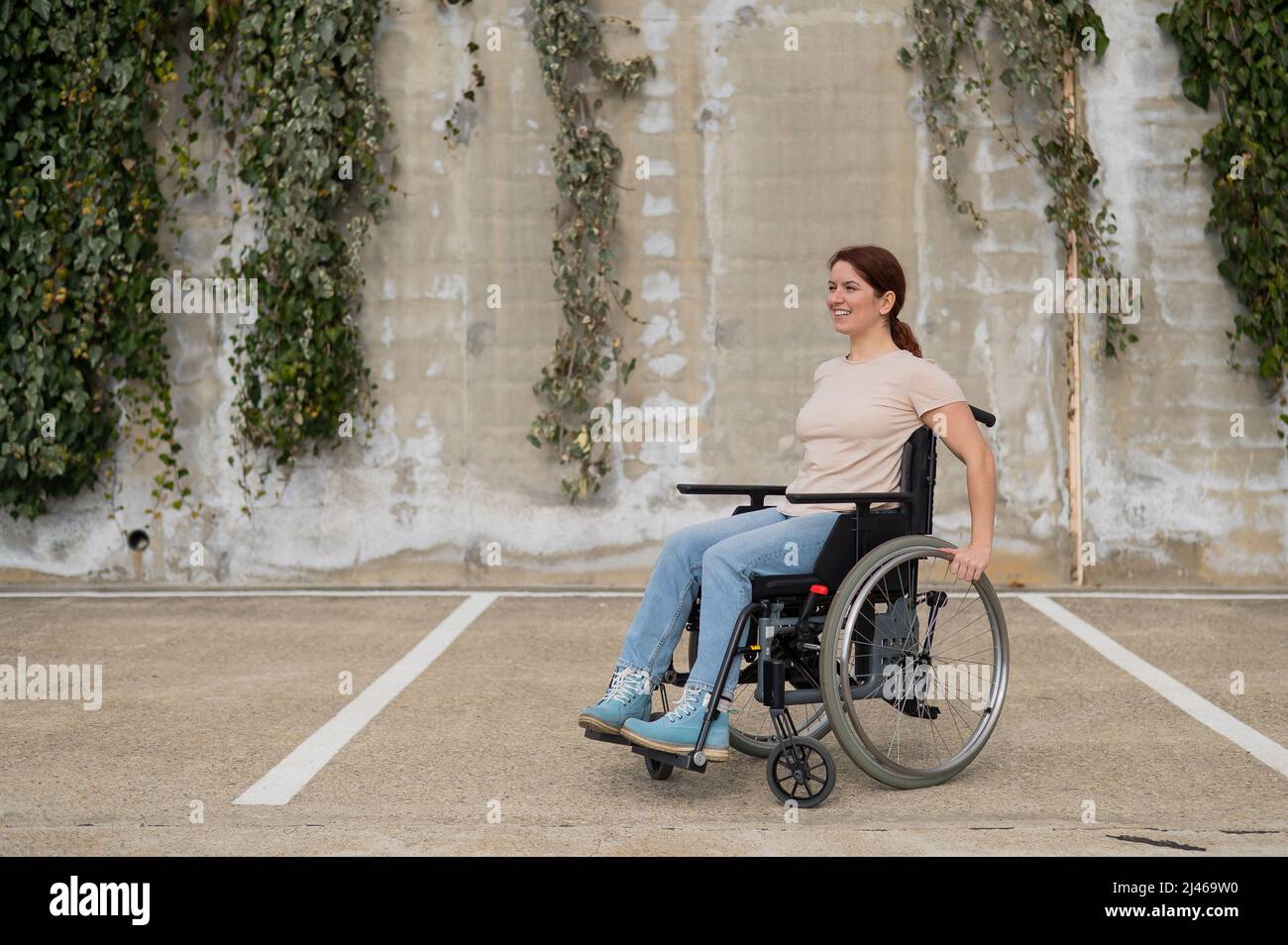 Woman riding a wheelchair in a parking lot Stock Photo - Alamy