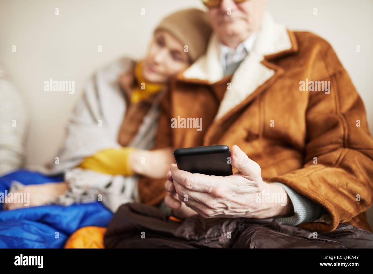 Close up of senior man hiding in shelter and holding phone with no ...