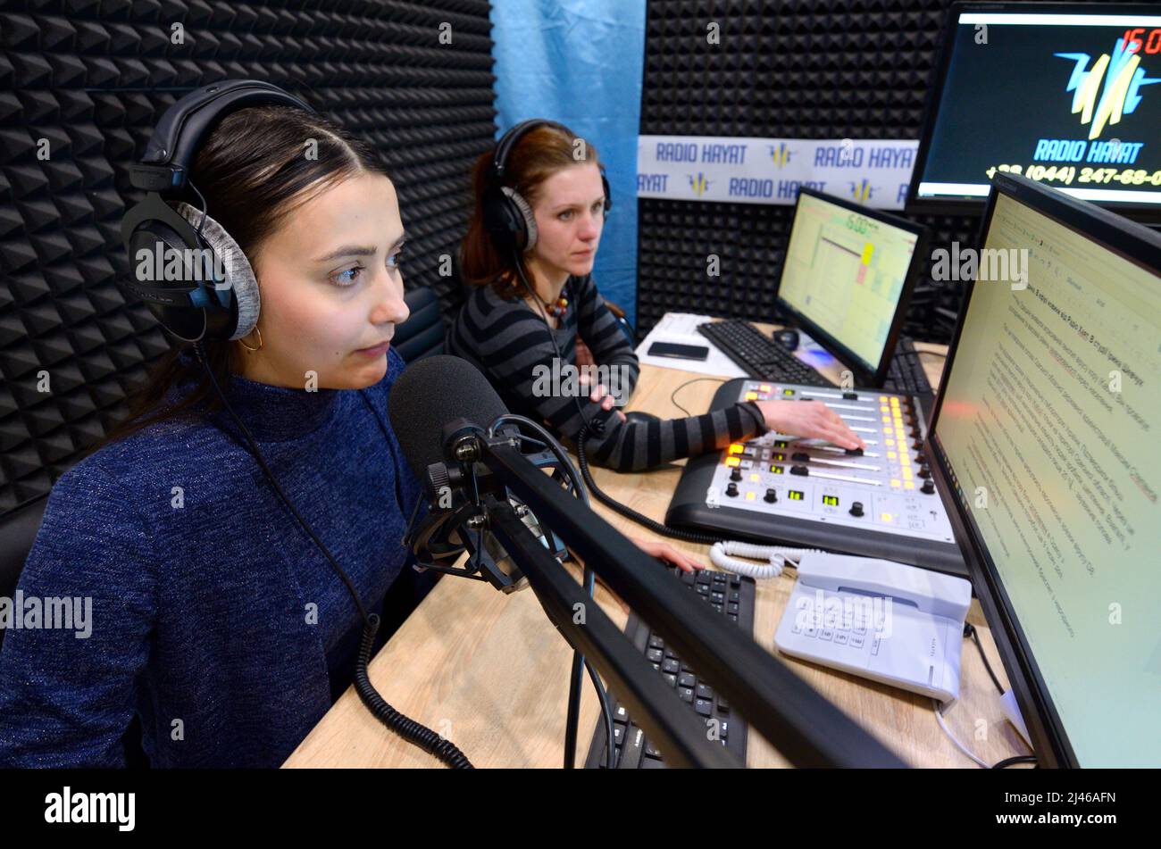 Sound engineer regulating level of sound with studio sound mixer at a radio studio while girl ...