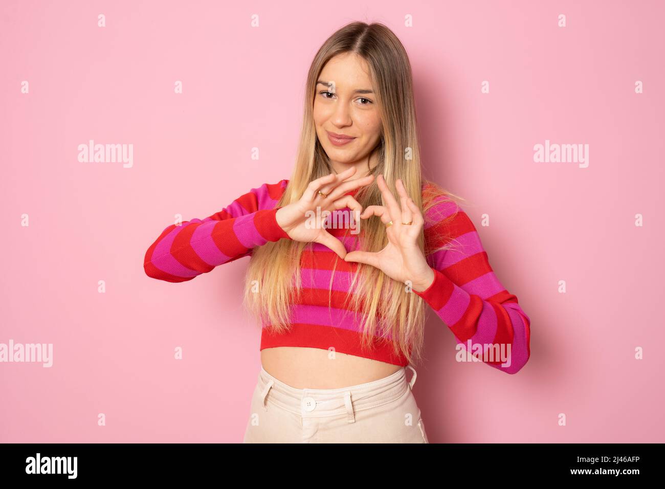 Attractive young caucasian girl feels happy and romantic shapes heart ...