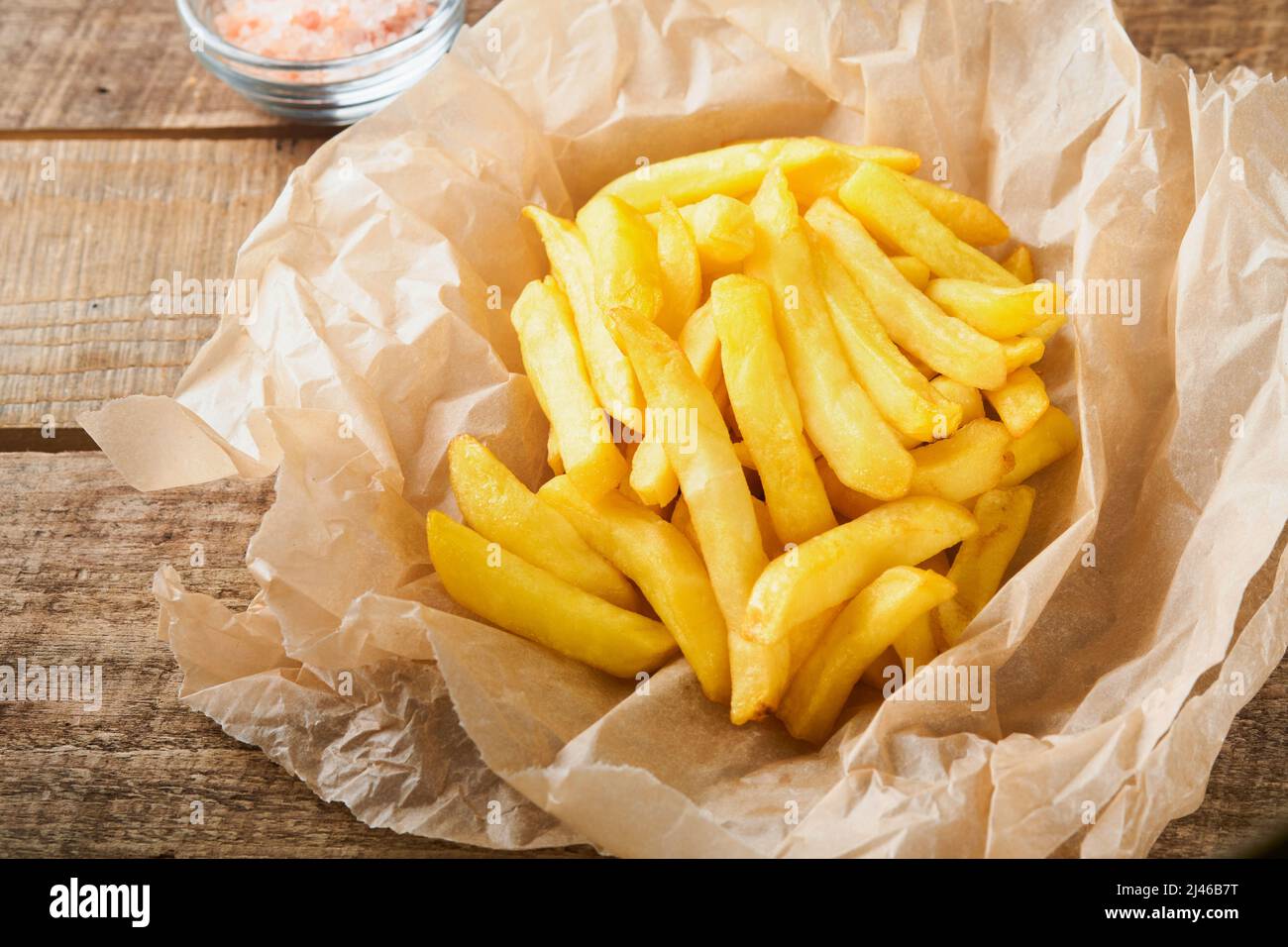 French fries. Tasty French fries server on parchment paper on wooden ...