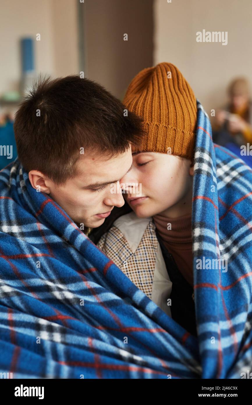 Vertical portrait of loving Caucasian couple hiding in refugee shelter ...
