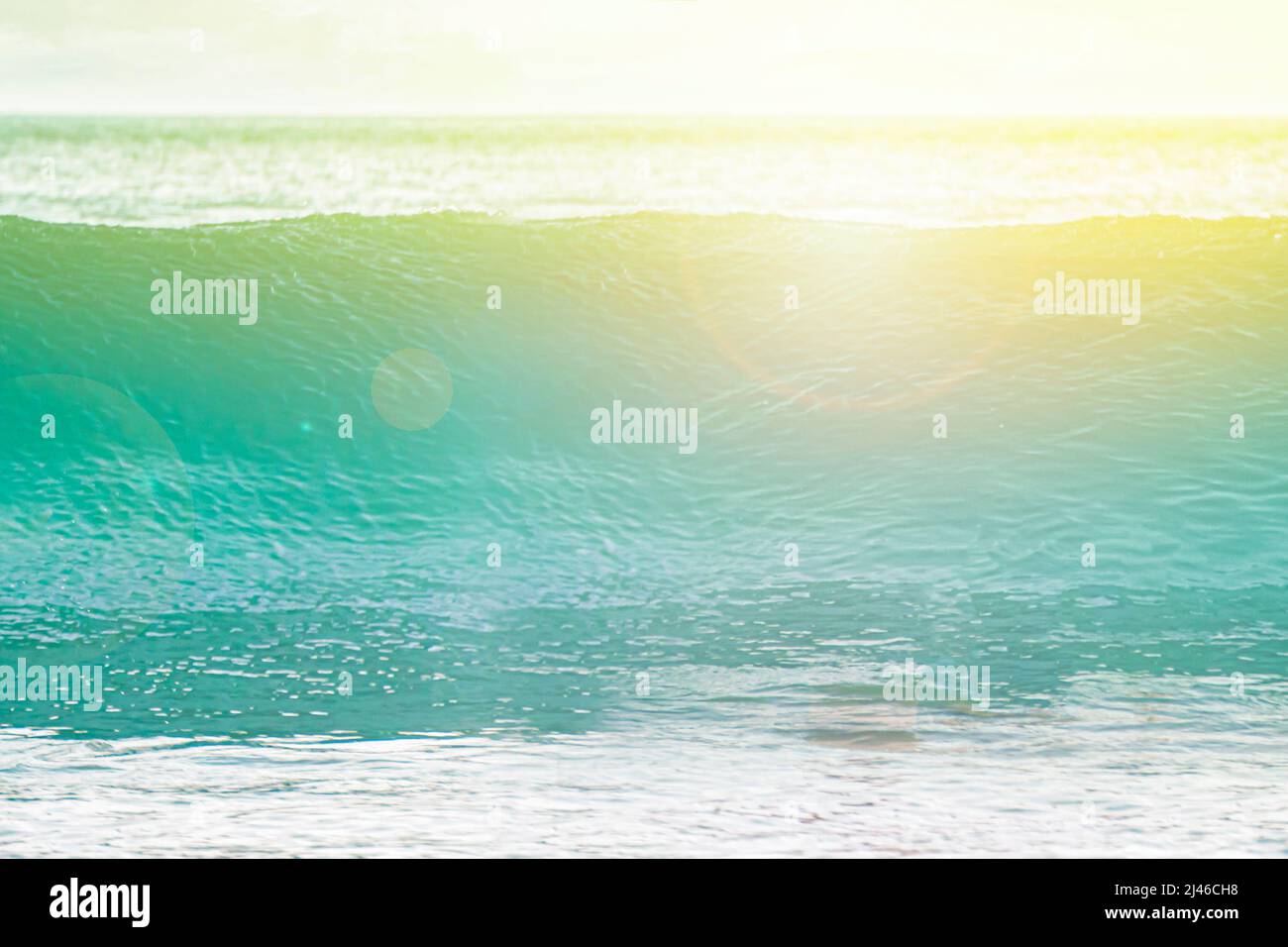 a beautiful sea wave on the beach, a smooth empty background of turquoise green with a sun glare ...