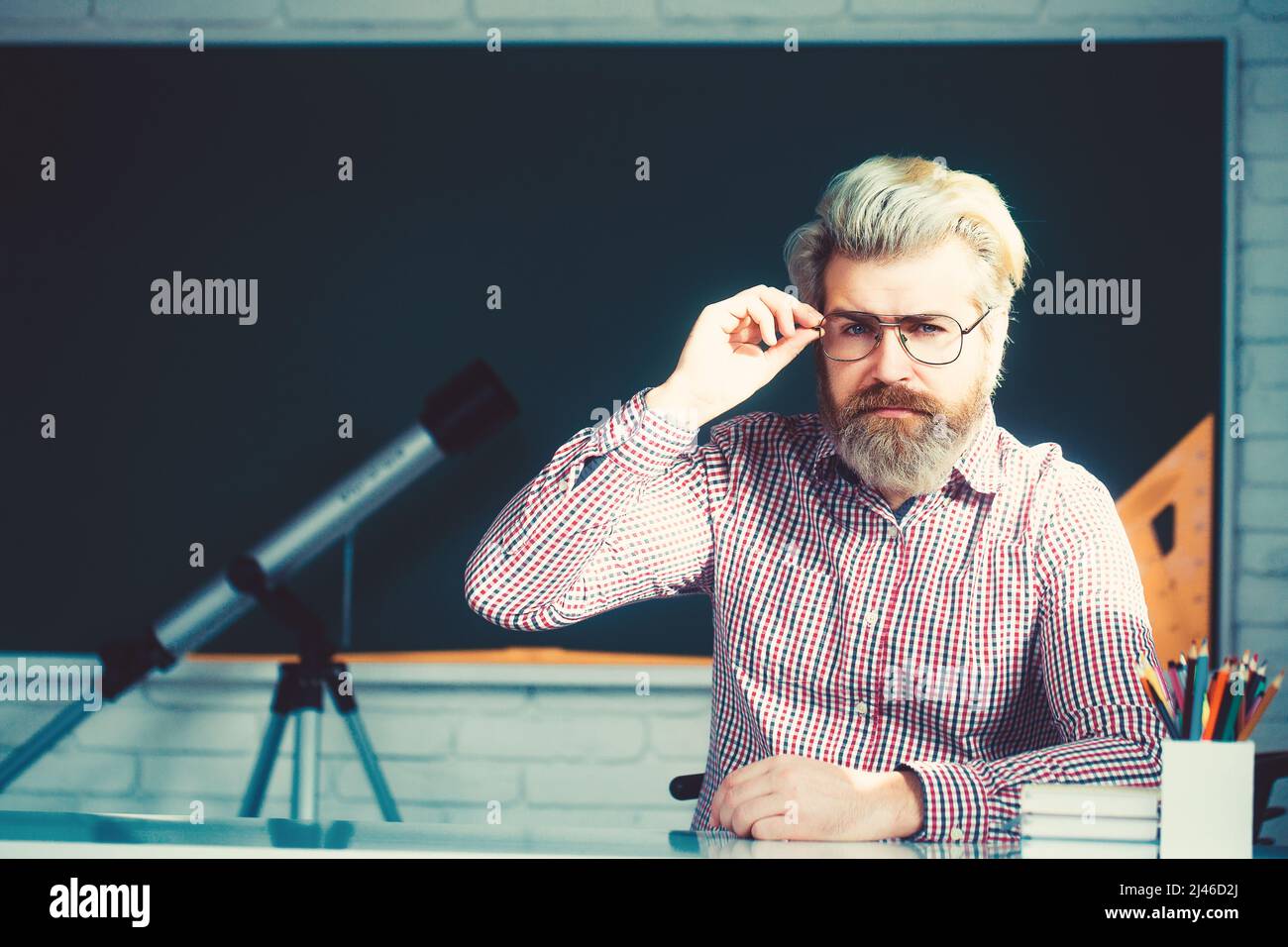 Young professor holding pile of books looking over his glasses Stock ...