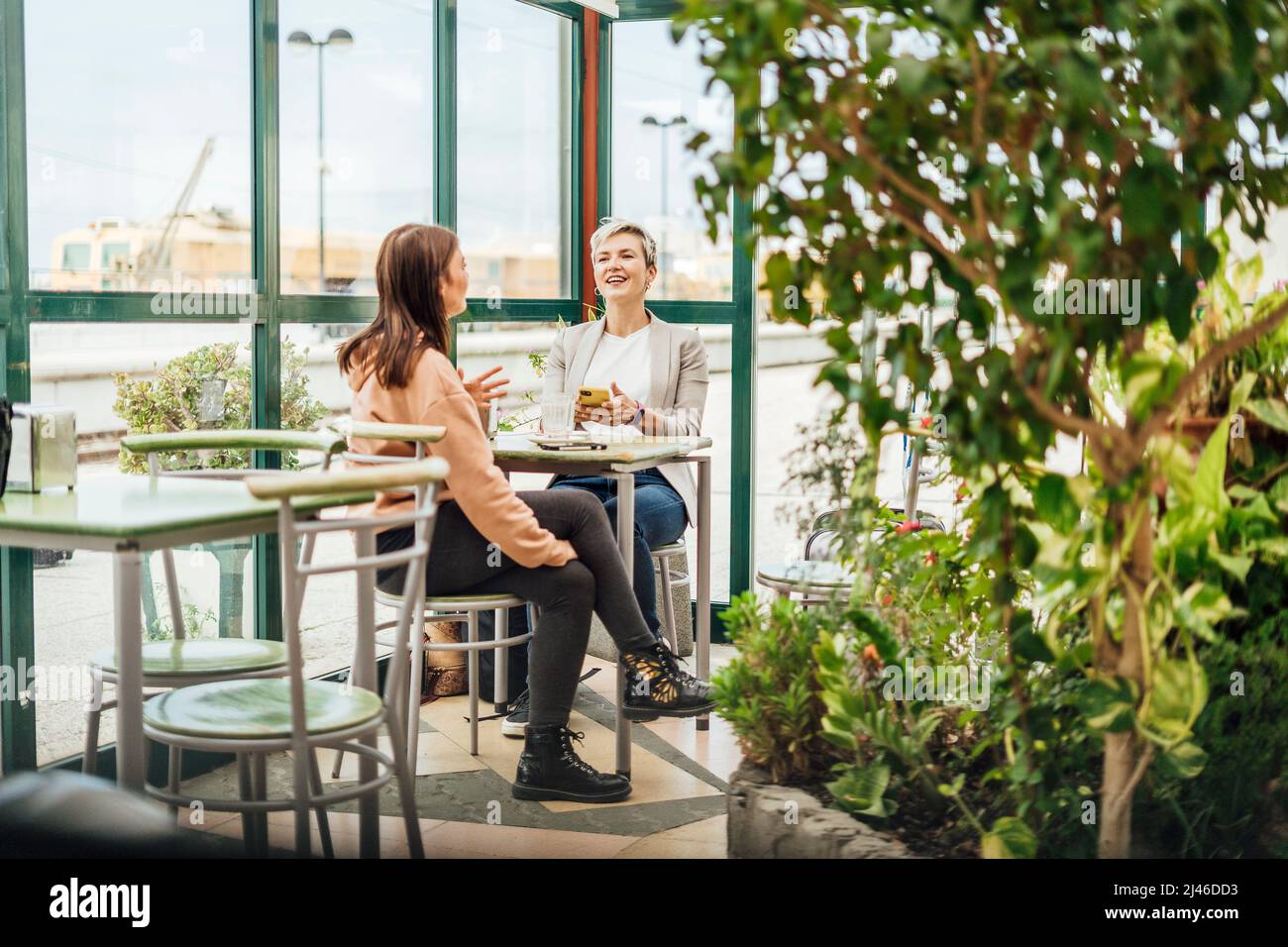 Two female friends drinking coffee and enjoying time in the cafe at ...
