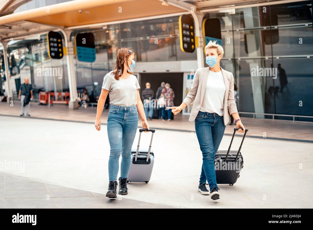 Traveling women in protective masks talking when leaving the airport at ...