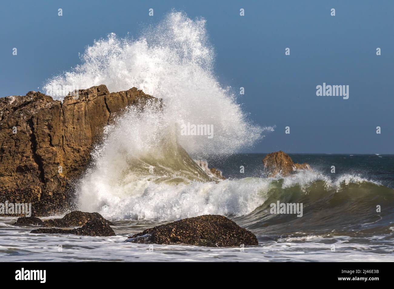 Large wave breaking against giant rock formation offshore near Malibu ...