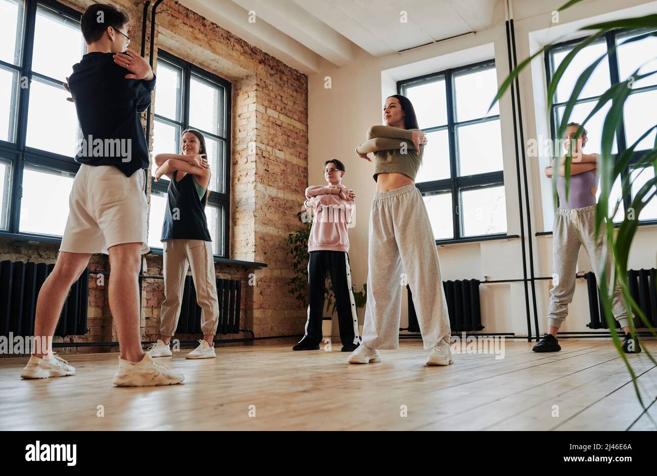 Group of teenage performers in activewear repeating vogue dancing ...