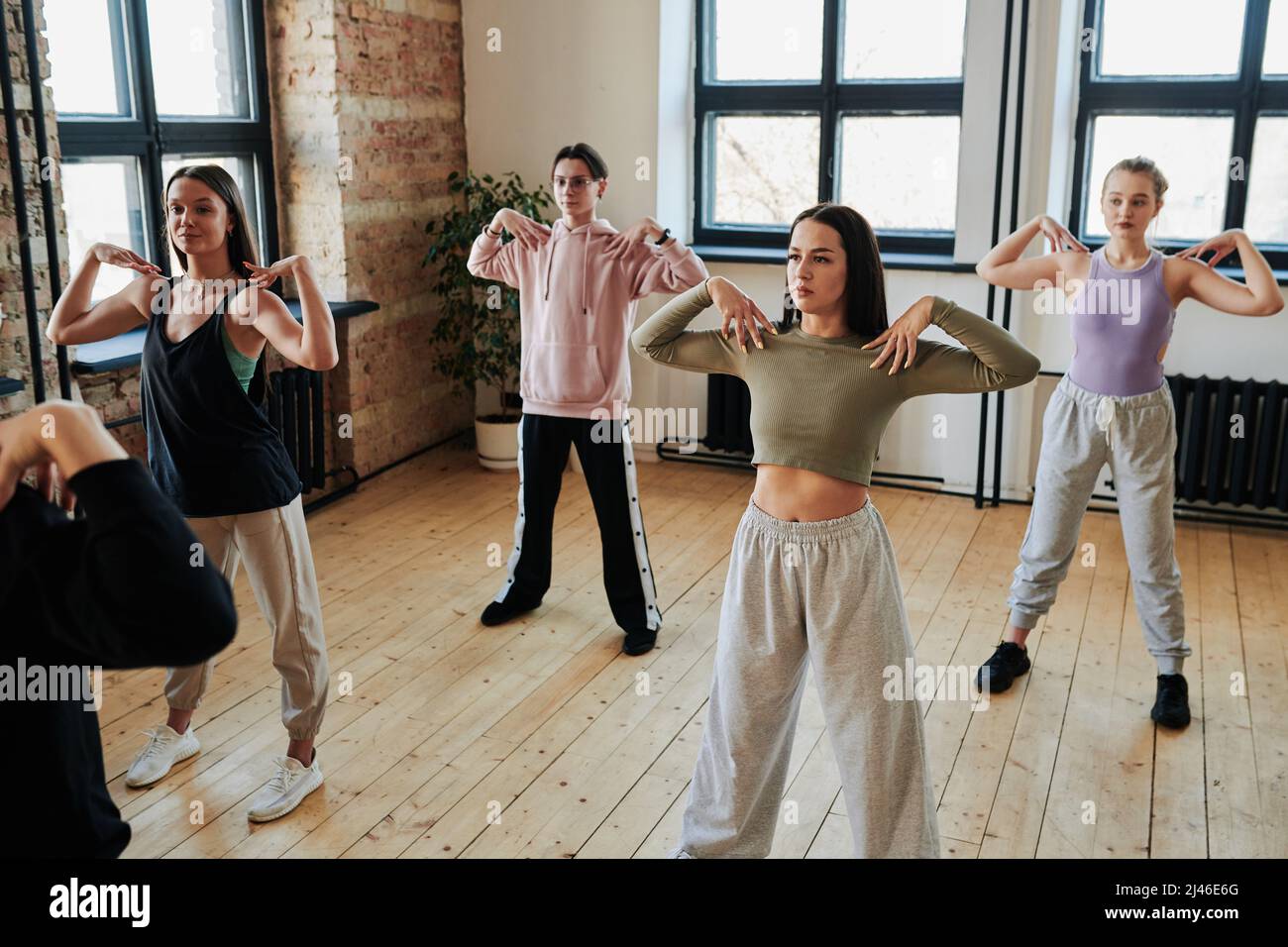 Large group of teenagers exercising in spacious loft studio with their ...