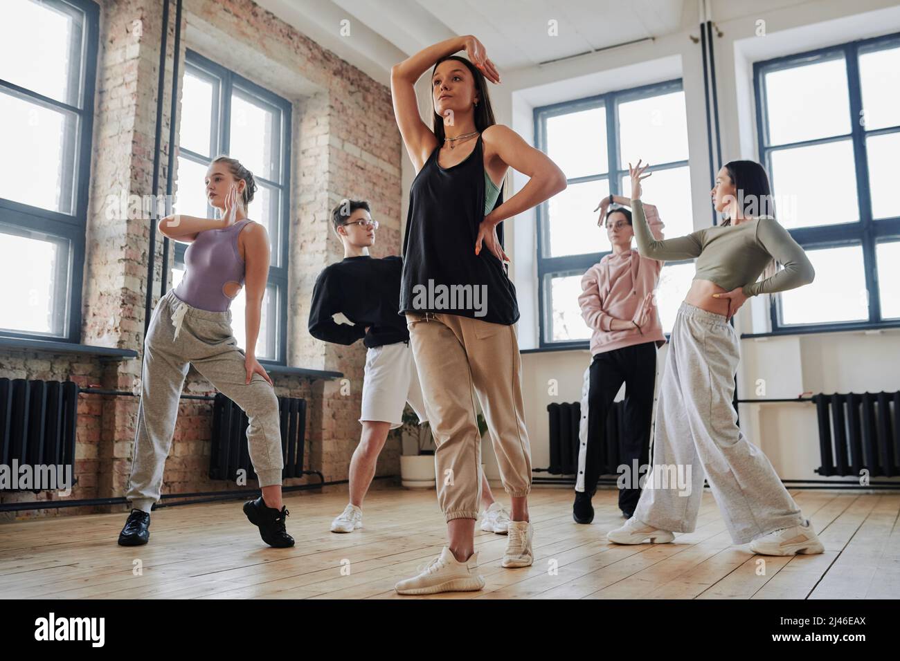 Youthful female performer with arm raised over head standing in front ...