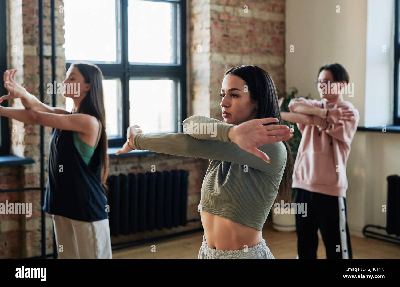 Two active teenage girls and guy crossing stretched arms in front of ...