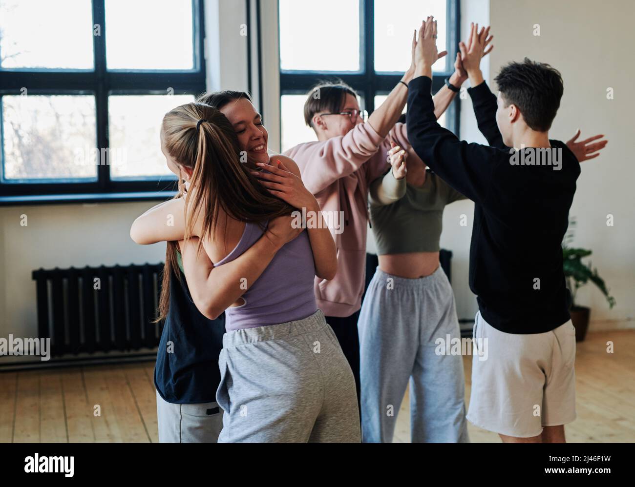 Group of contemporary teenage friends giving hugs and high five to each ...