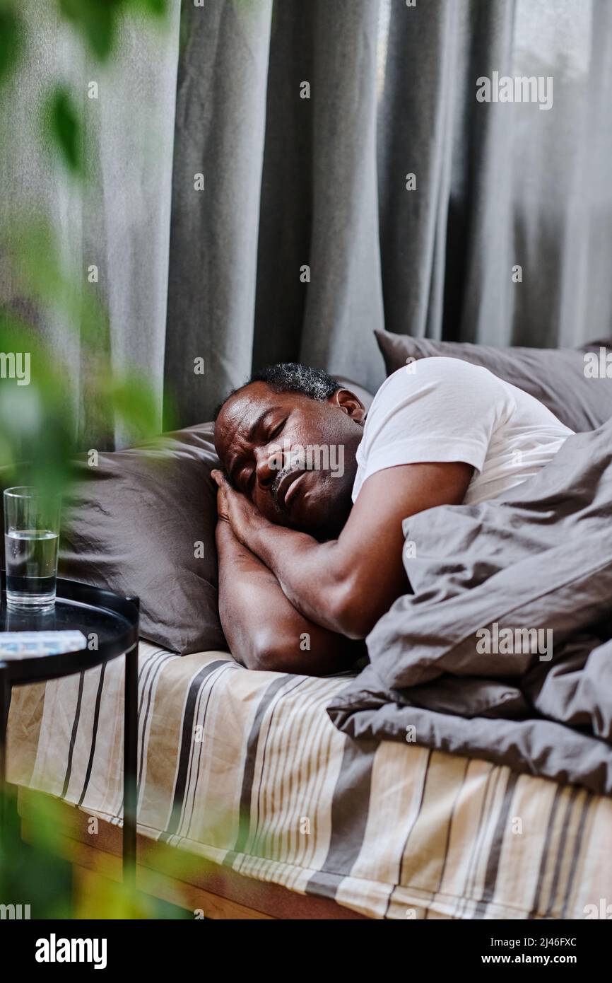 Tired mature African American man sleeping peacefully in bed in the ...