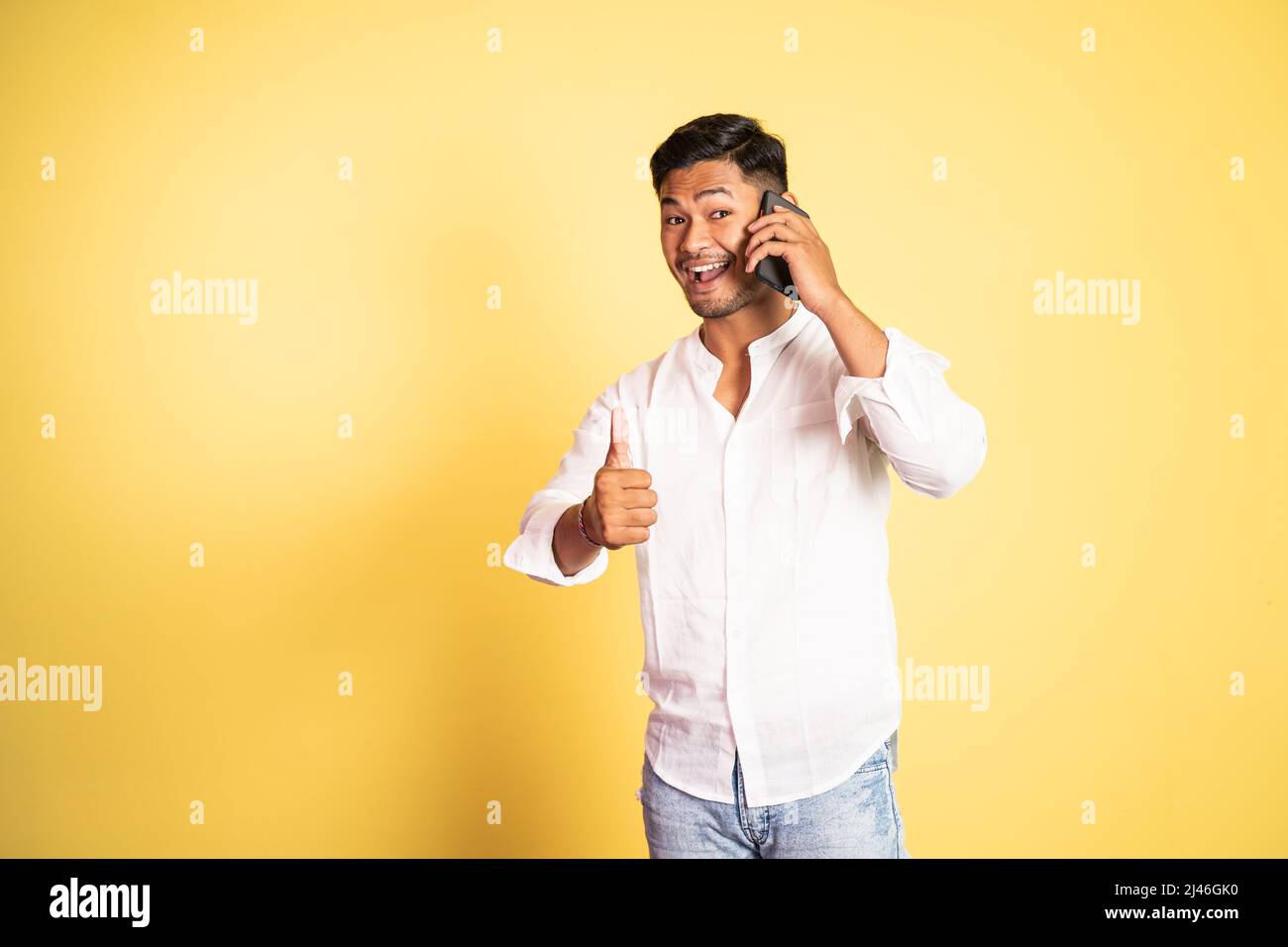 excited young man wearing white shirt calling with thumbs up Stock ...