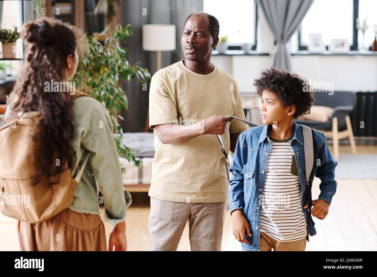 Senior retired African American man helping his grandson take off ...