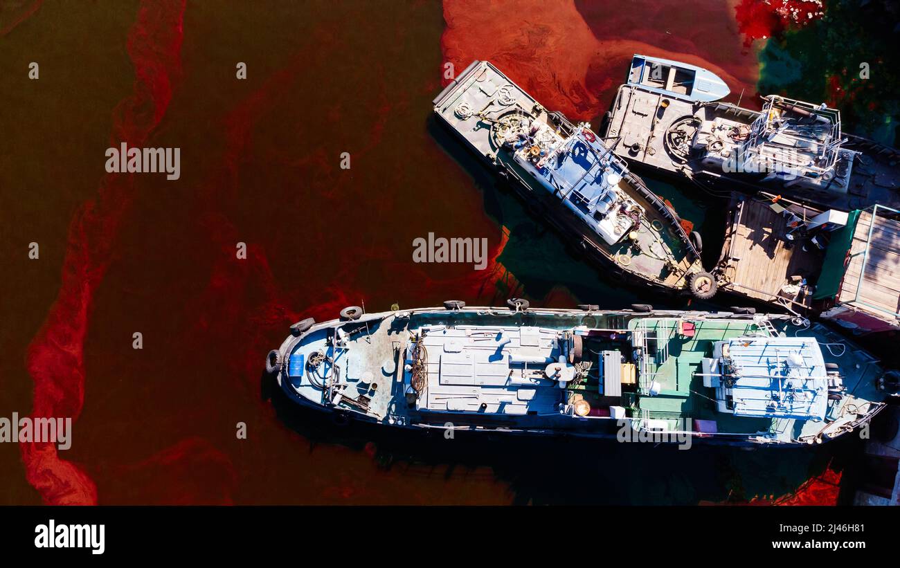 An old rusty red and brown barge in red water. Urban and industrial ...