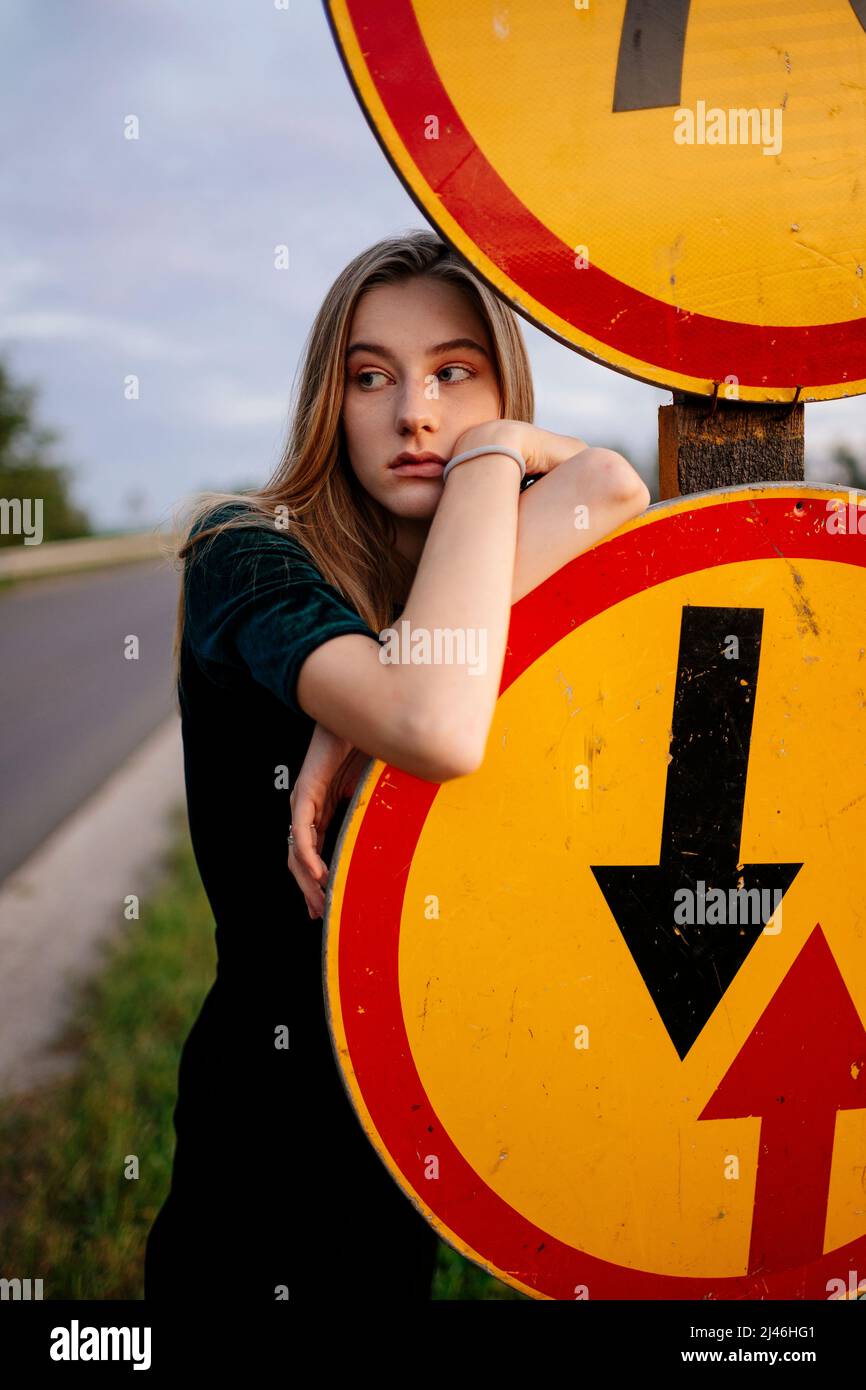 Woman on the road looking at traffic signs Stock Photo - Alamy