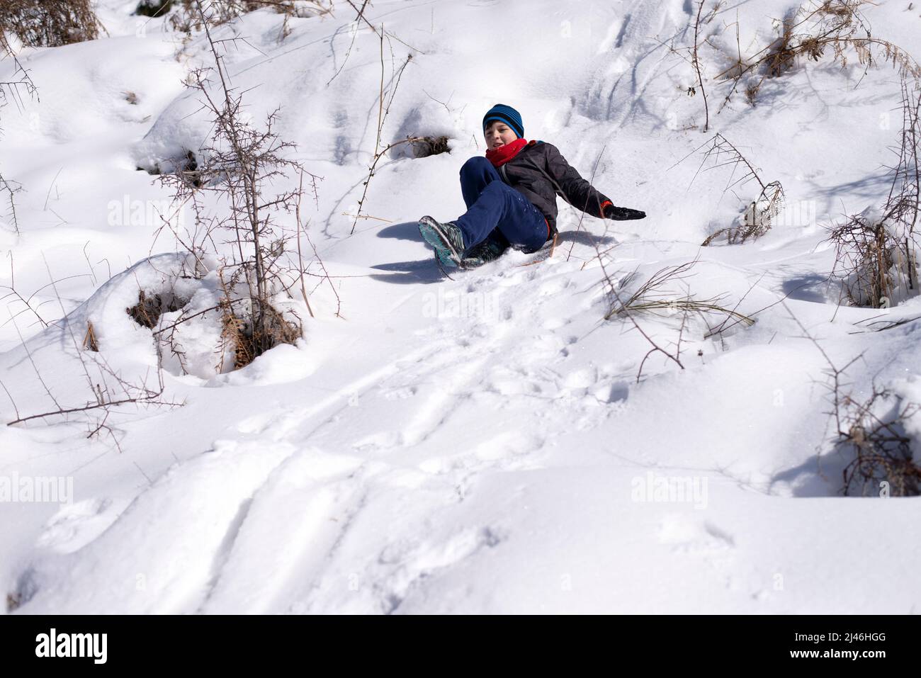 Boy slides down from the snow slope. Enjoying winter sledding time ...