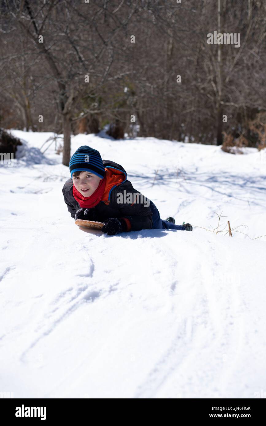 Boy slides down from the snow slope Stock Photo - Alamy