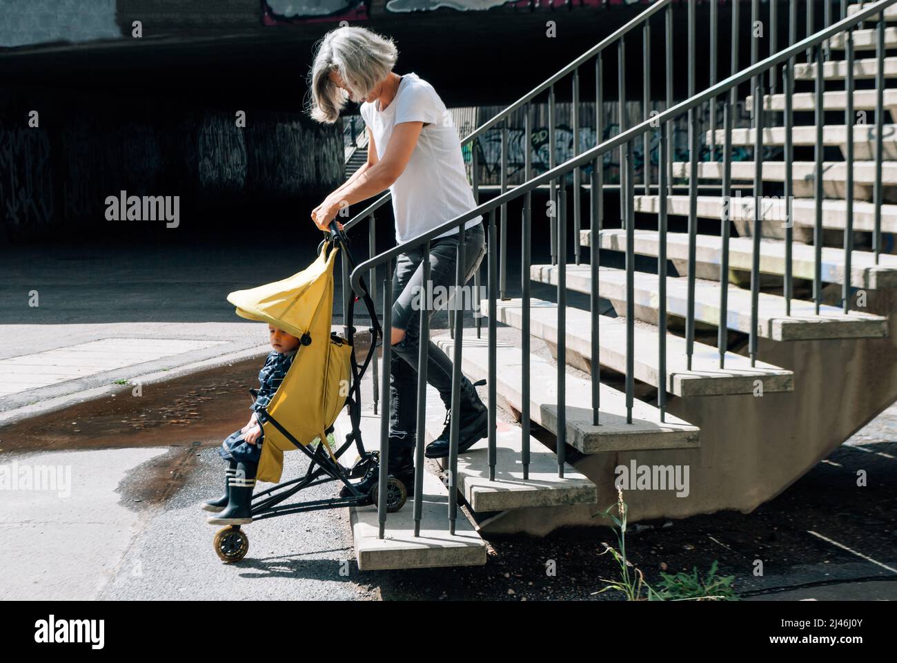 Woman lifts stroller on steps of street stairs and lack of ramp Stock ...