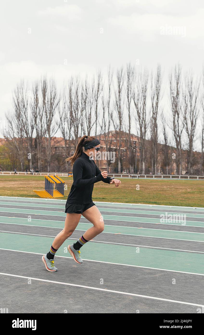 woman running on a running track watching the watch Stock Photo - Alamy