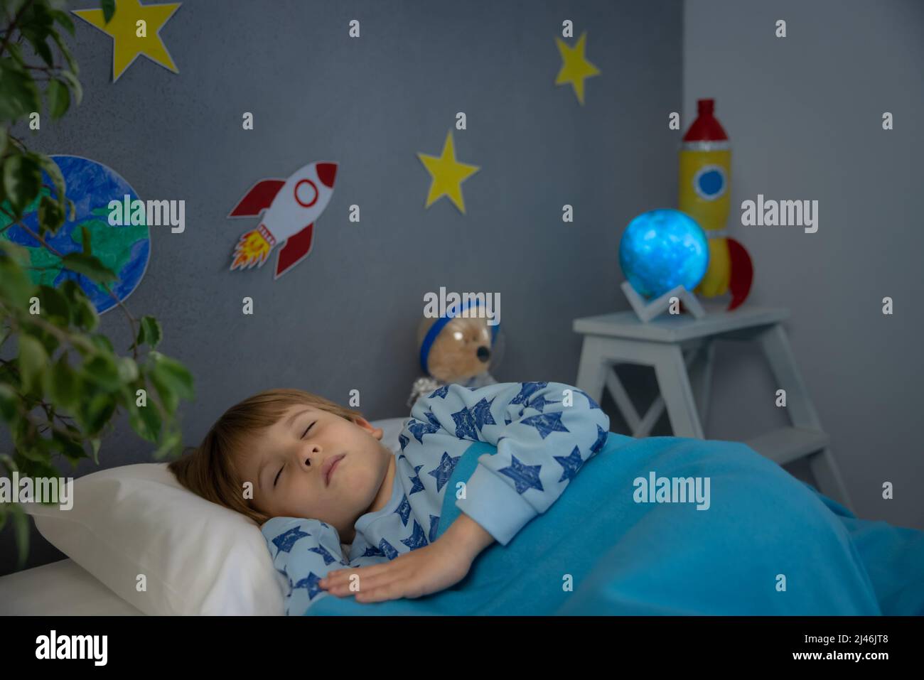 Happy child sleeping with toy rocket and teddy bear. Kid pretend to be ...