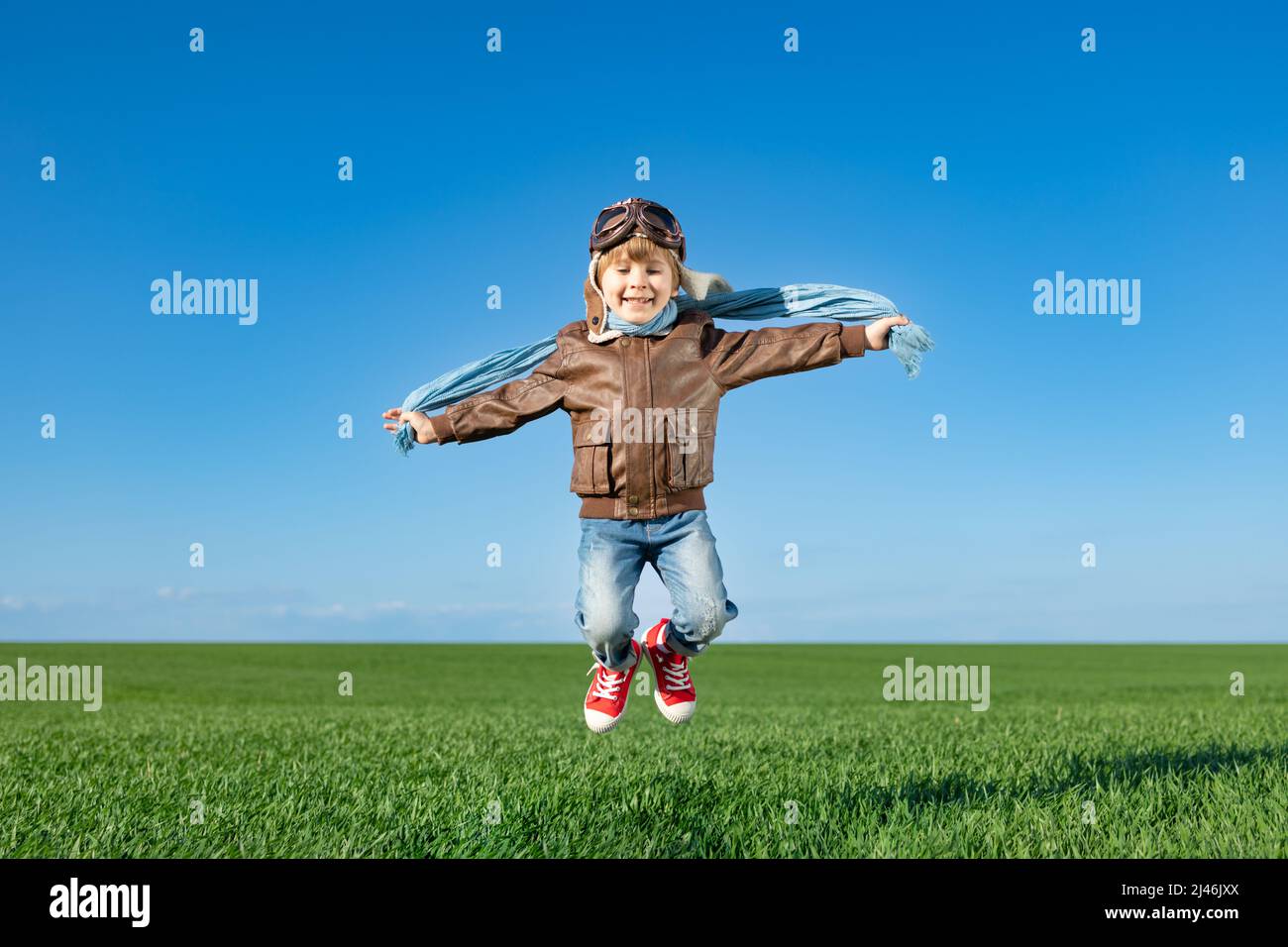 Happy child jumping outdoor in spring green field. Kid having fun ...