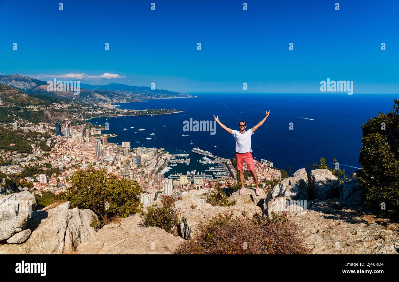 A handsome young man stands and jubilantly with his hands raised on a ...